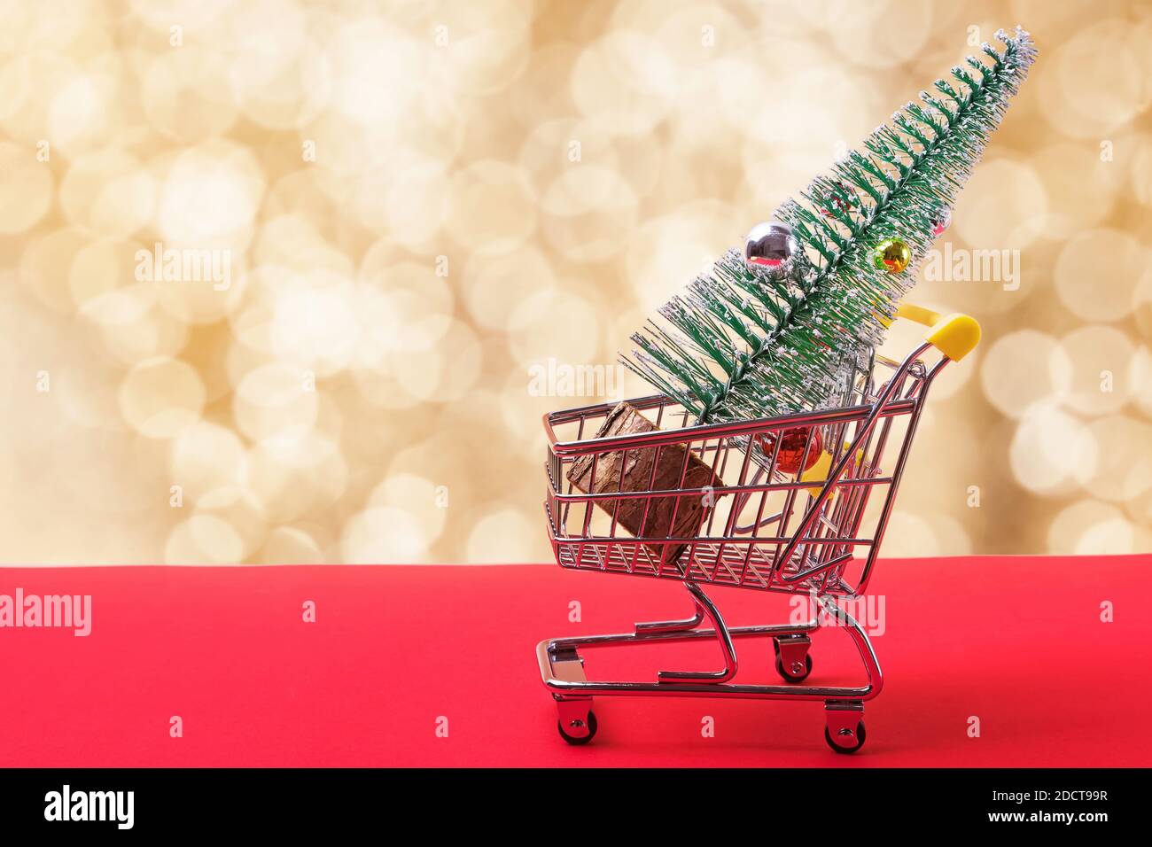 Small trolley with Christmas tree on the blurred lights background ...