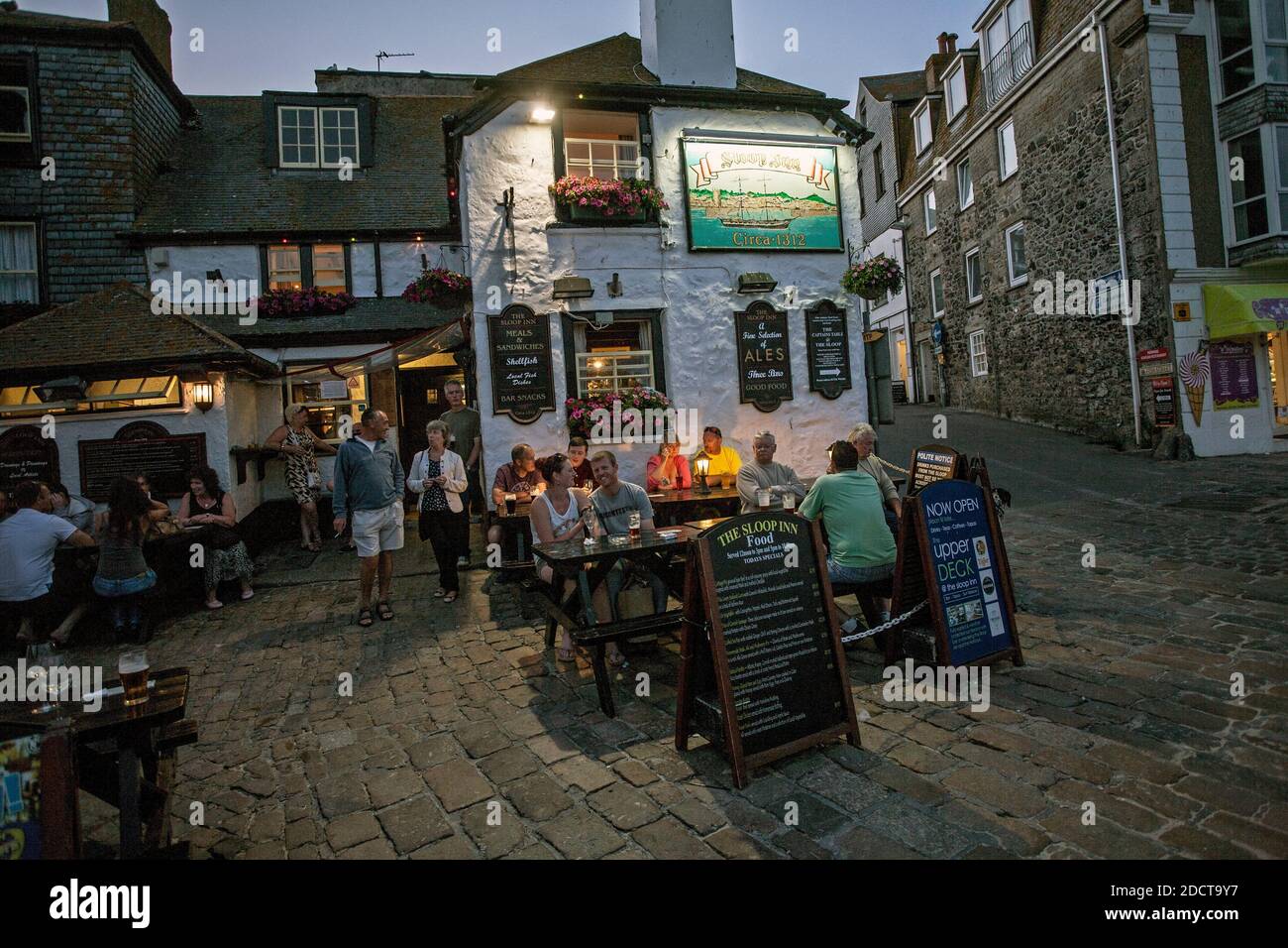People sitting outside the Pub Sloop Inn in St. Ive's harbour, Cornwall ...