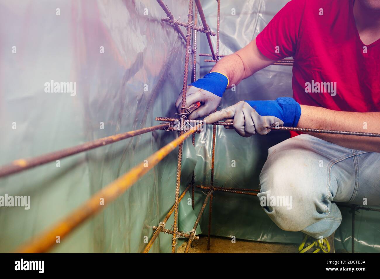 Closeup of a man hands knit metal rods framework with bars and wiring ...