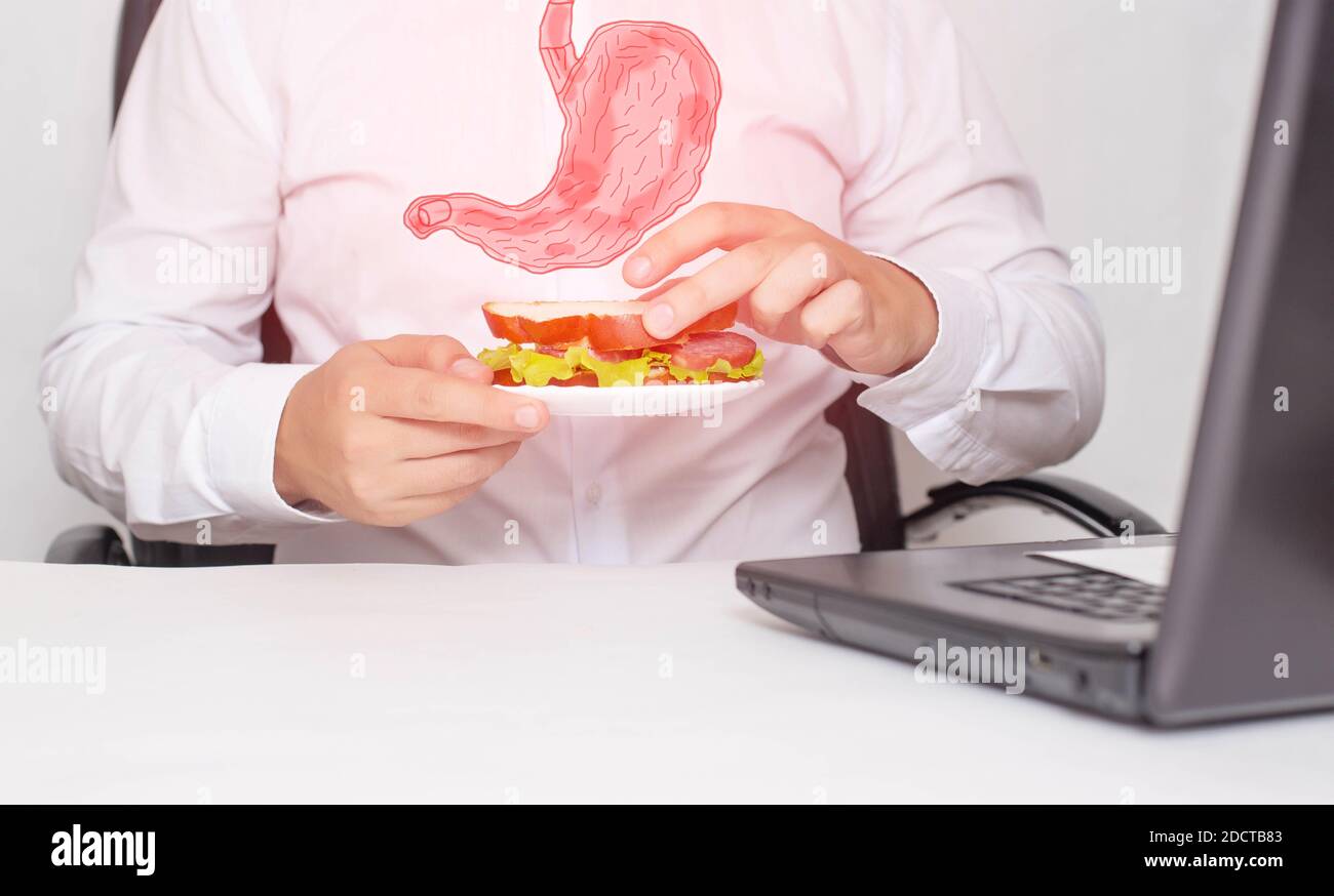 A male office worker holds a sandwich in his hands during lunch. The ...