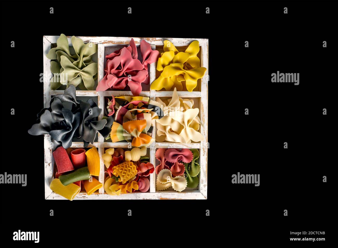 wooden box with various types of Italian pasta on a white table ...