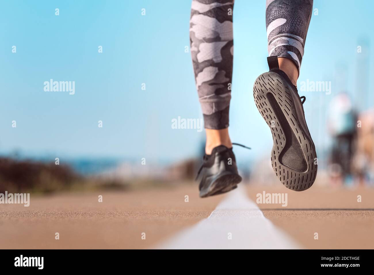 Slim woman athlete running at road. Runner feet running on road closeup ...