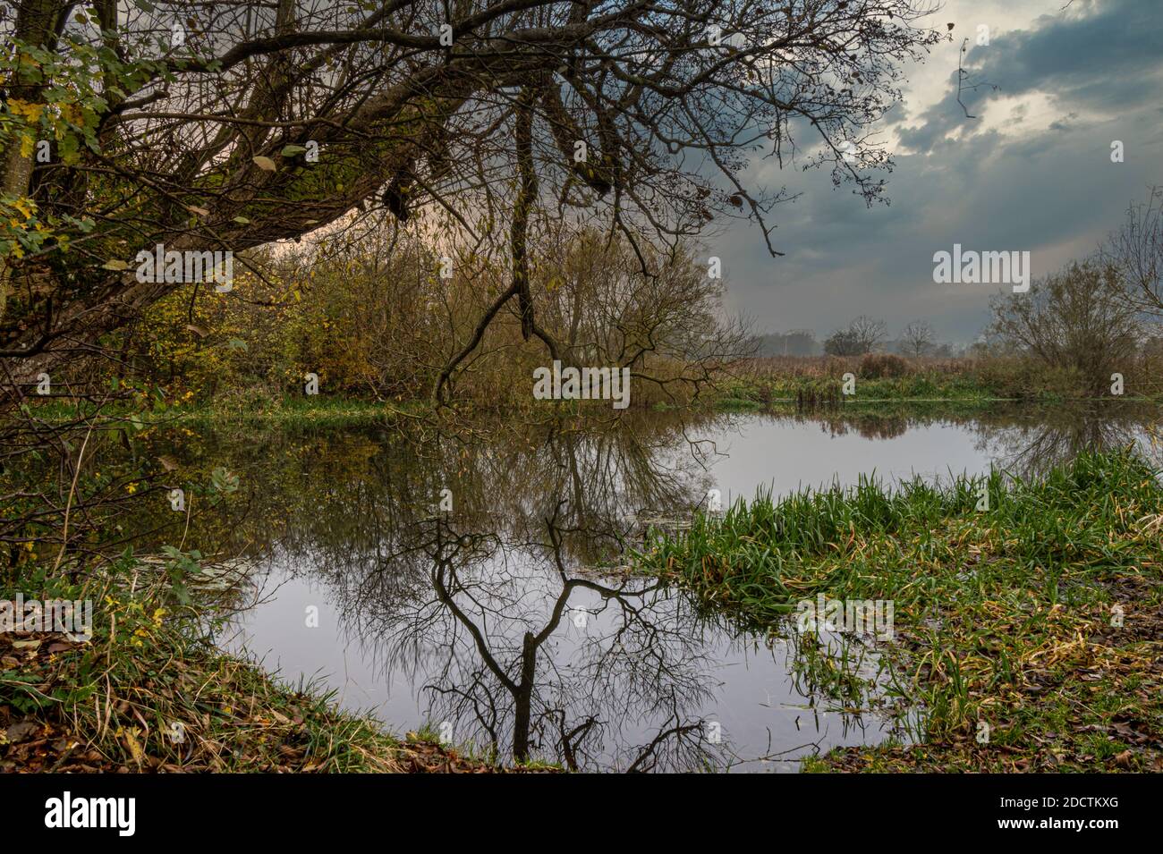 Reflections in a river with a dramatic sunset in the background ...