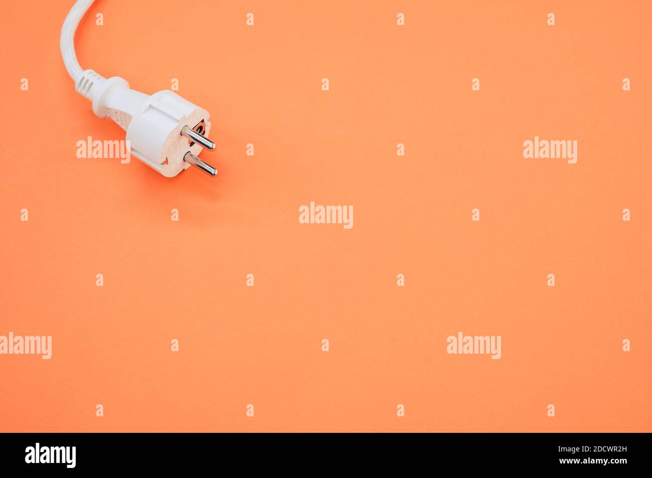 A high angle shot of an electrical wire and plug on an orange surface ...