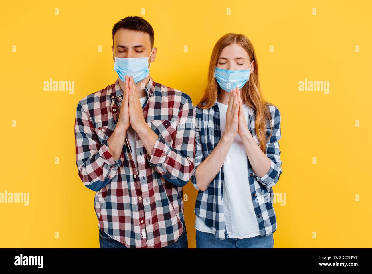 young man and a woman in medical protective masks, praying with prayer ...