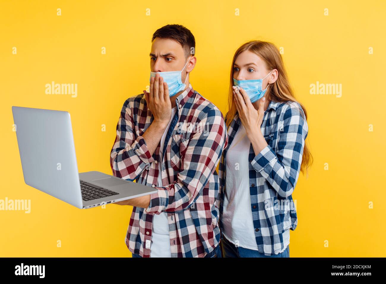 shocked man and woman in plaid shirts and medical protective masks on ...