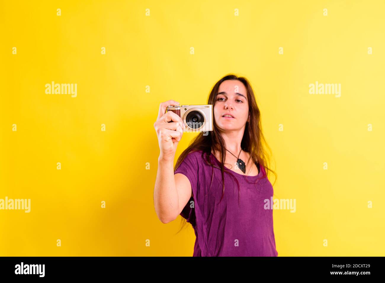 Young photography student girl holds a compact camera, isolated on ...