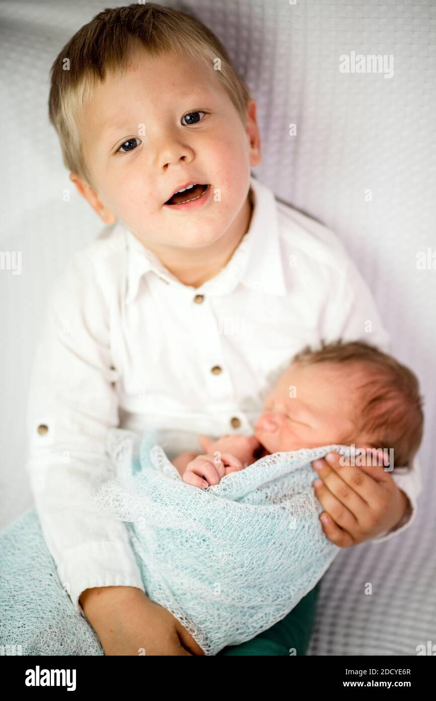 Three years old boy holding his newborn baby brother Stock Photo - Alamy