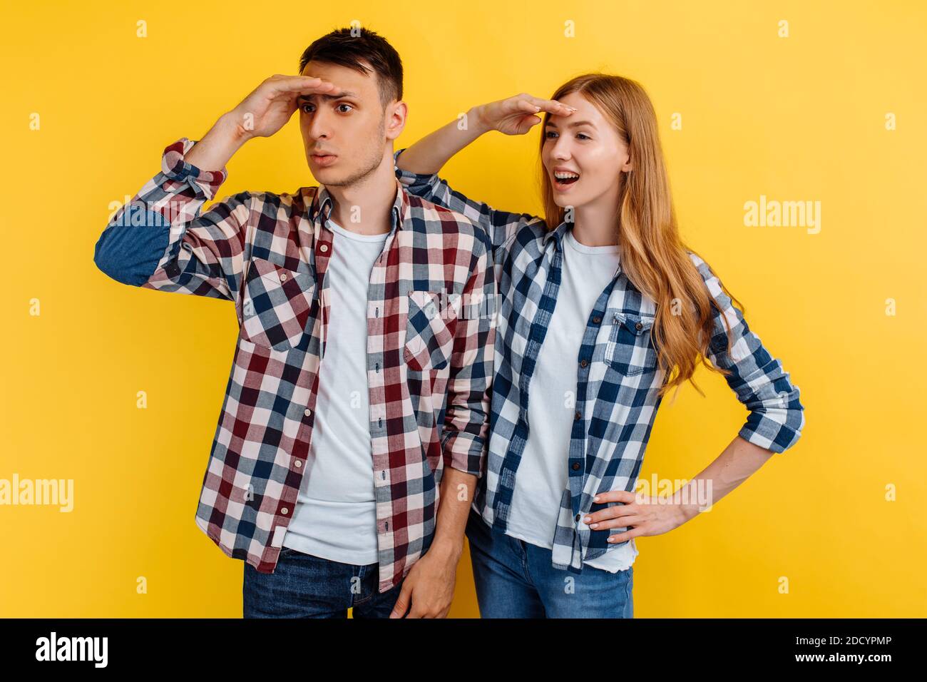 Young couple, man and woman, looking far away with hand above head, on ...