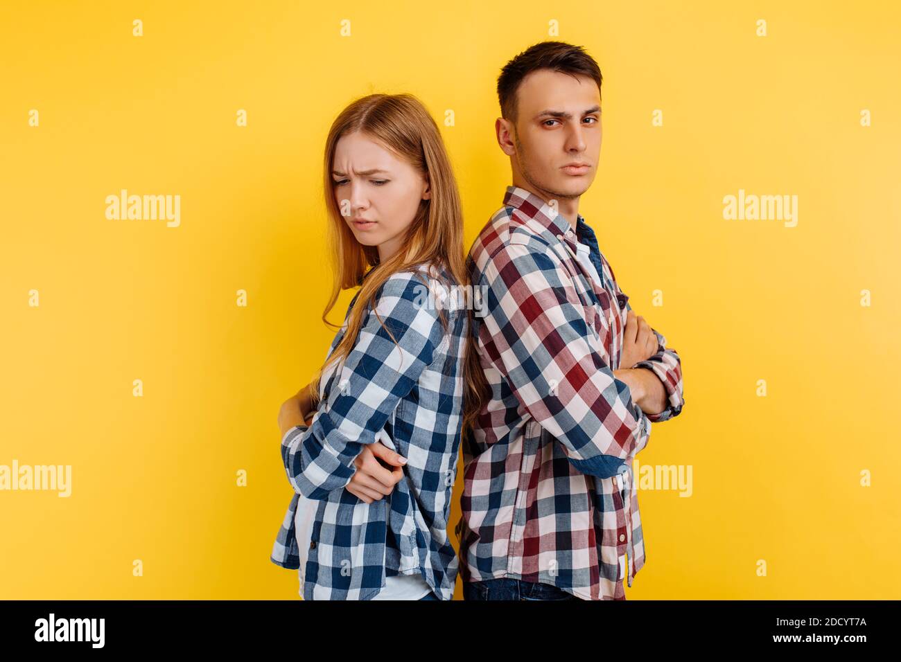 Offended angry young couple, man and woman standing back to each other ...