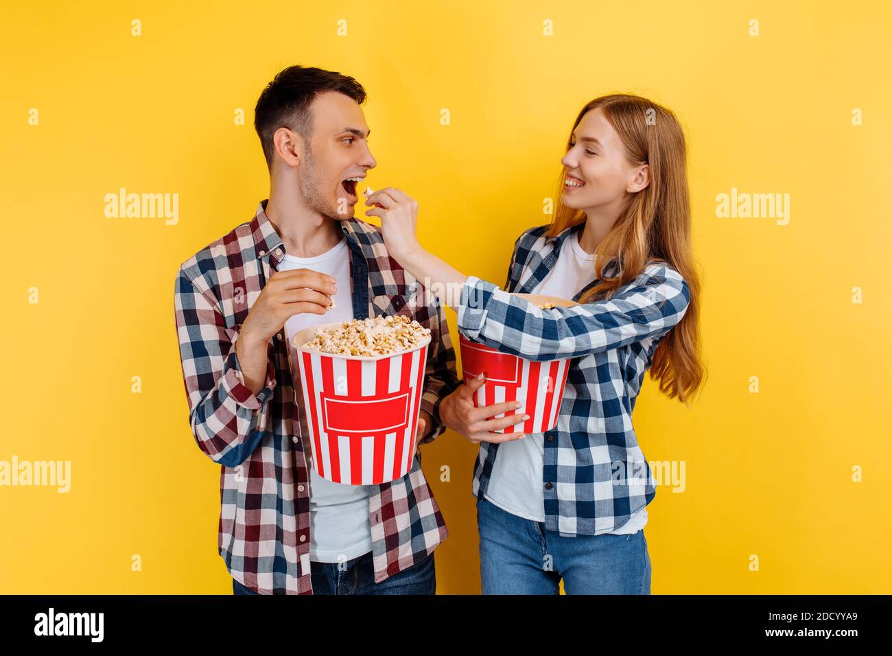 Happy excited young couple watching movie with popcorn on yellow ...