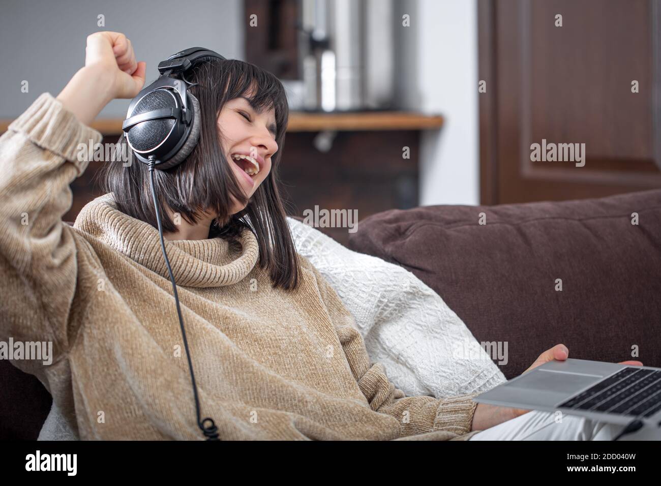 Beautiful girl in headphones listens to music and sings at home on the ...