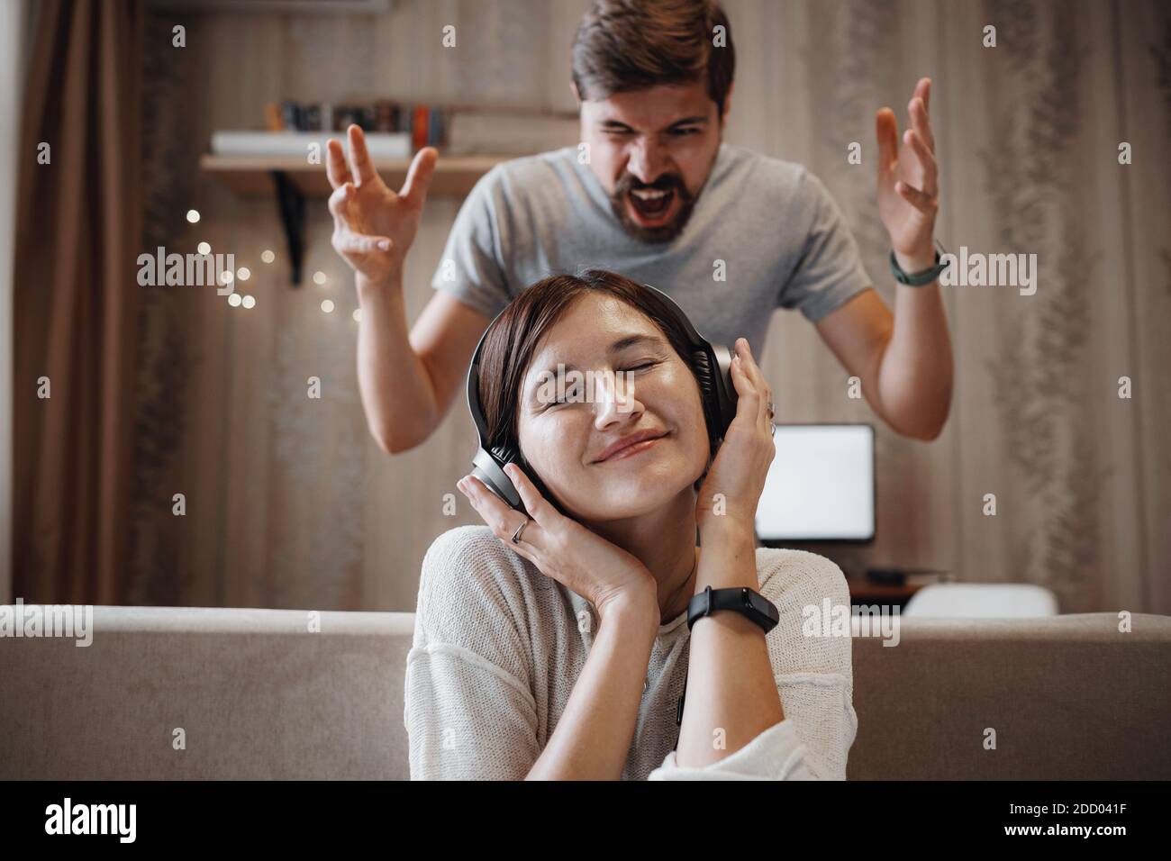 angry husband shouting at wife sitting on sofa and covering ears with ...