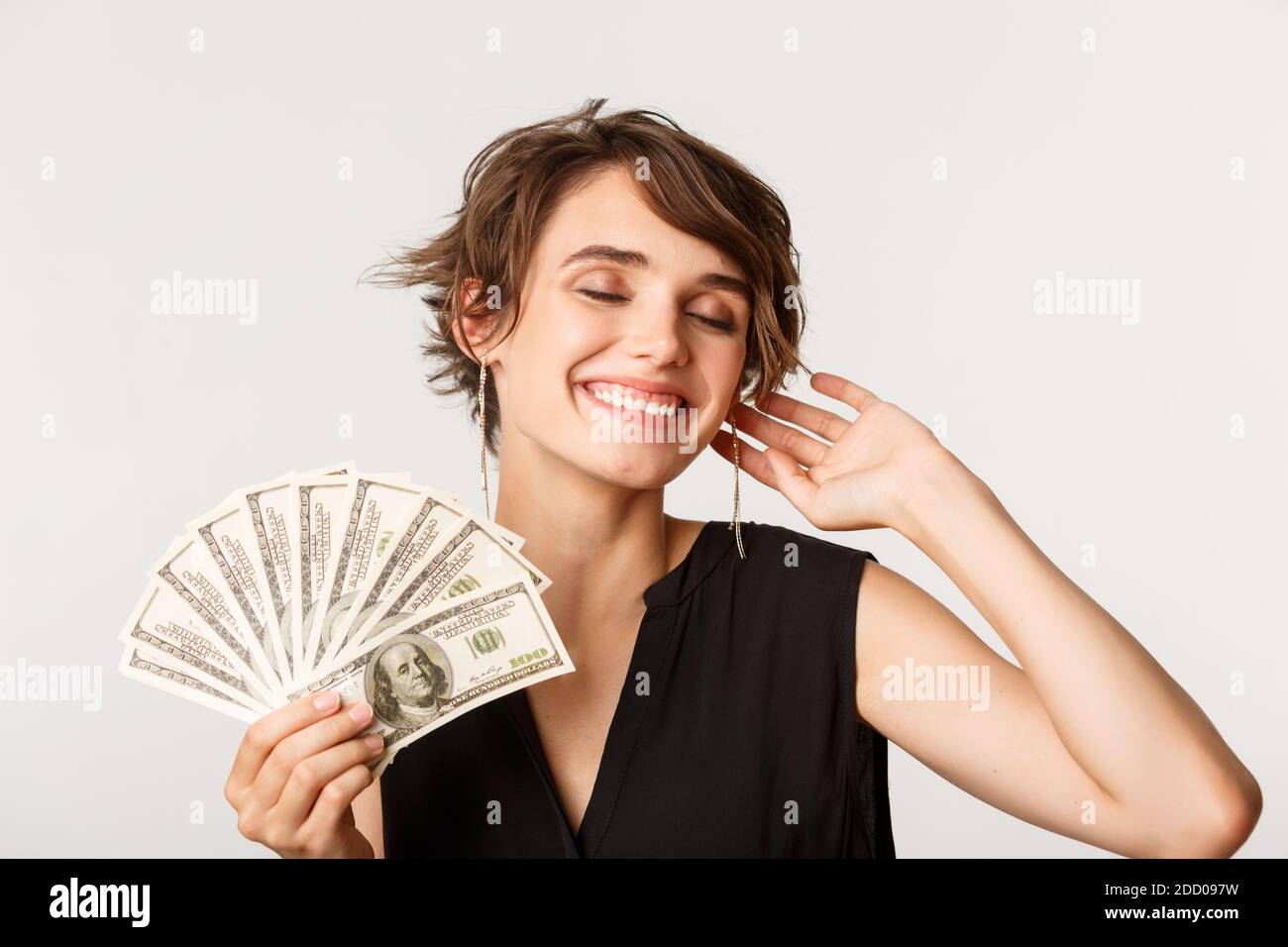 Carefree elegant rich woman smiling, showing money, standing over white ...