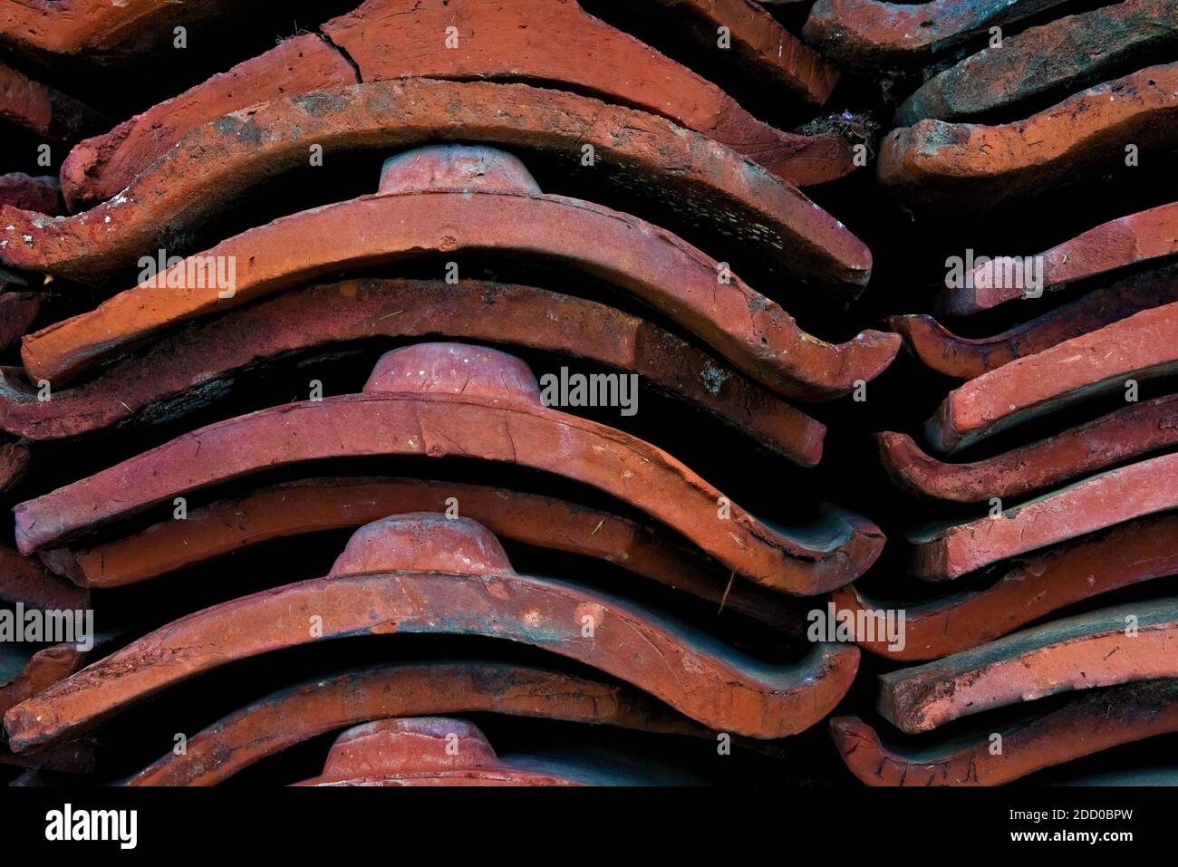Old weathered red clay roof tiles from Europe, stacked on top of each ...