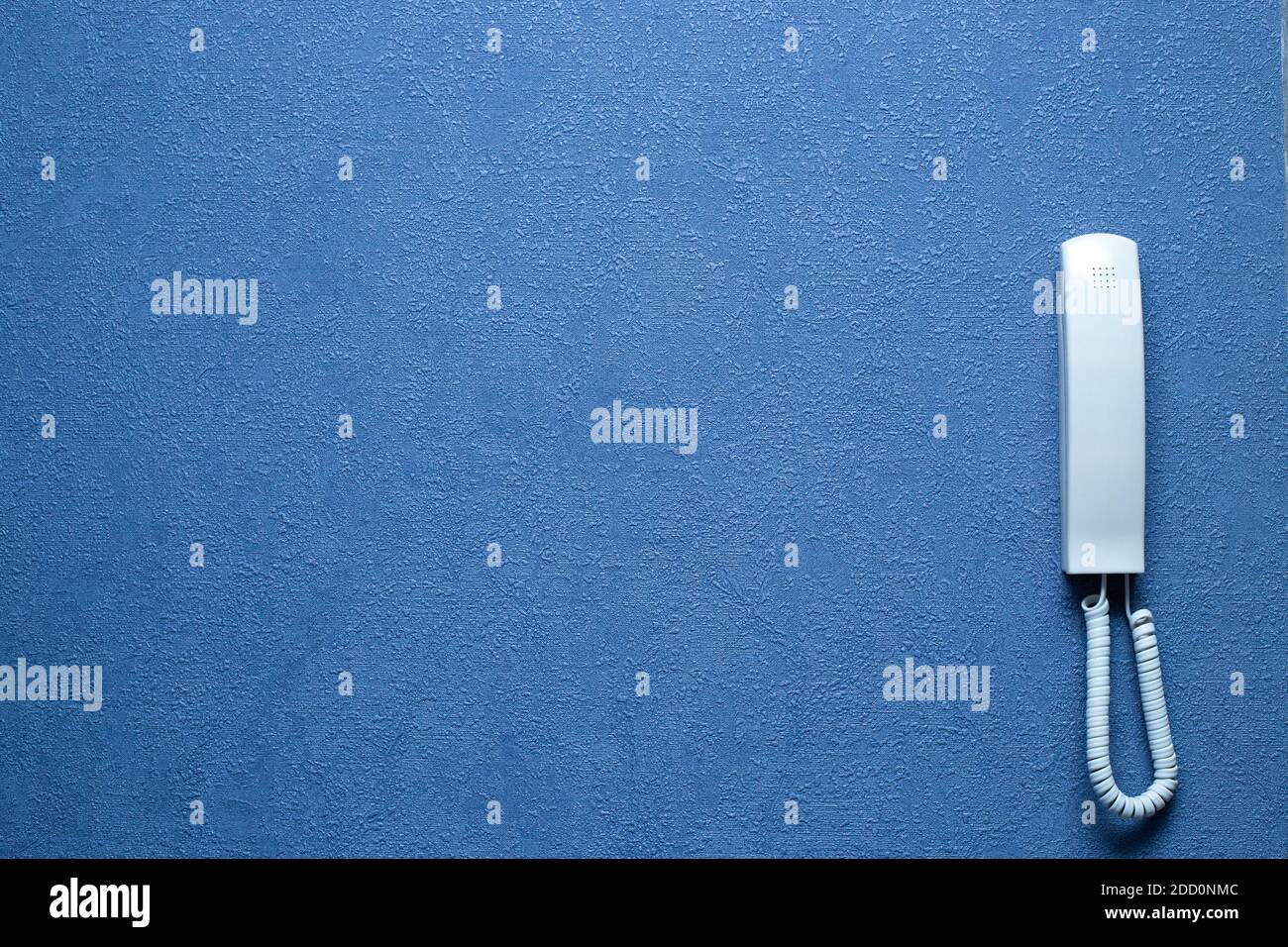 white intercom receiver on blue wall with copy space Stock Photo - Alamy
