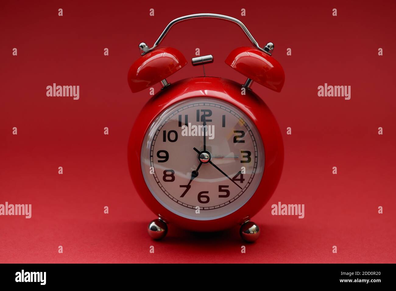 Red alarm clock on a red background Stock Photo - Alamy