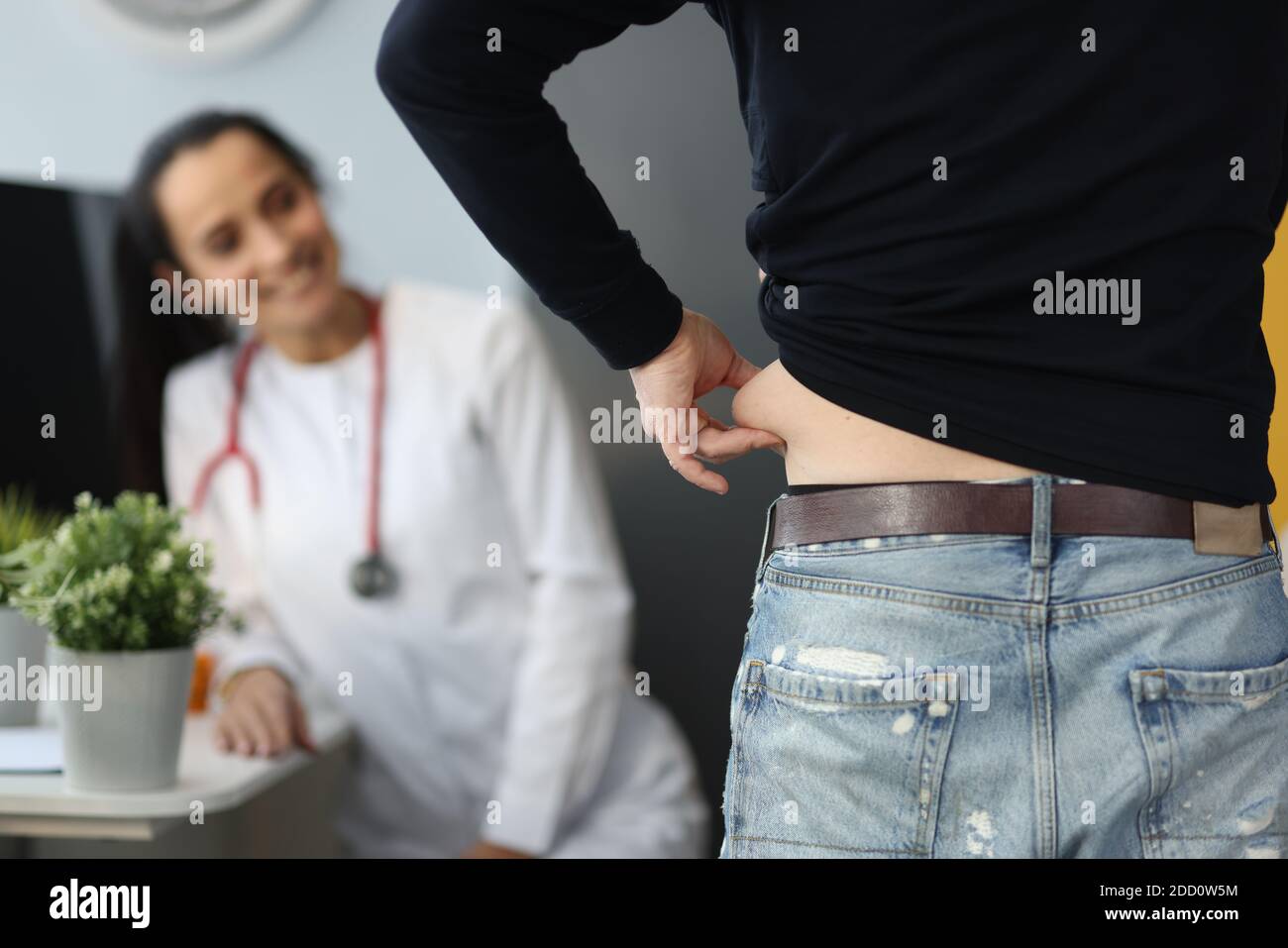 Man demonstrates cellulite on his sides to doctor Stock Photo - Alamy