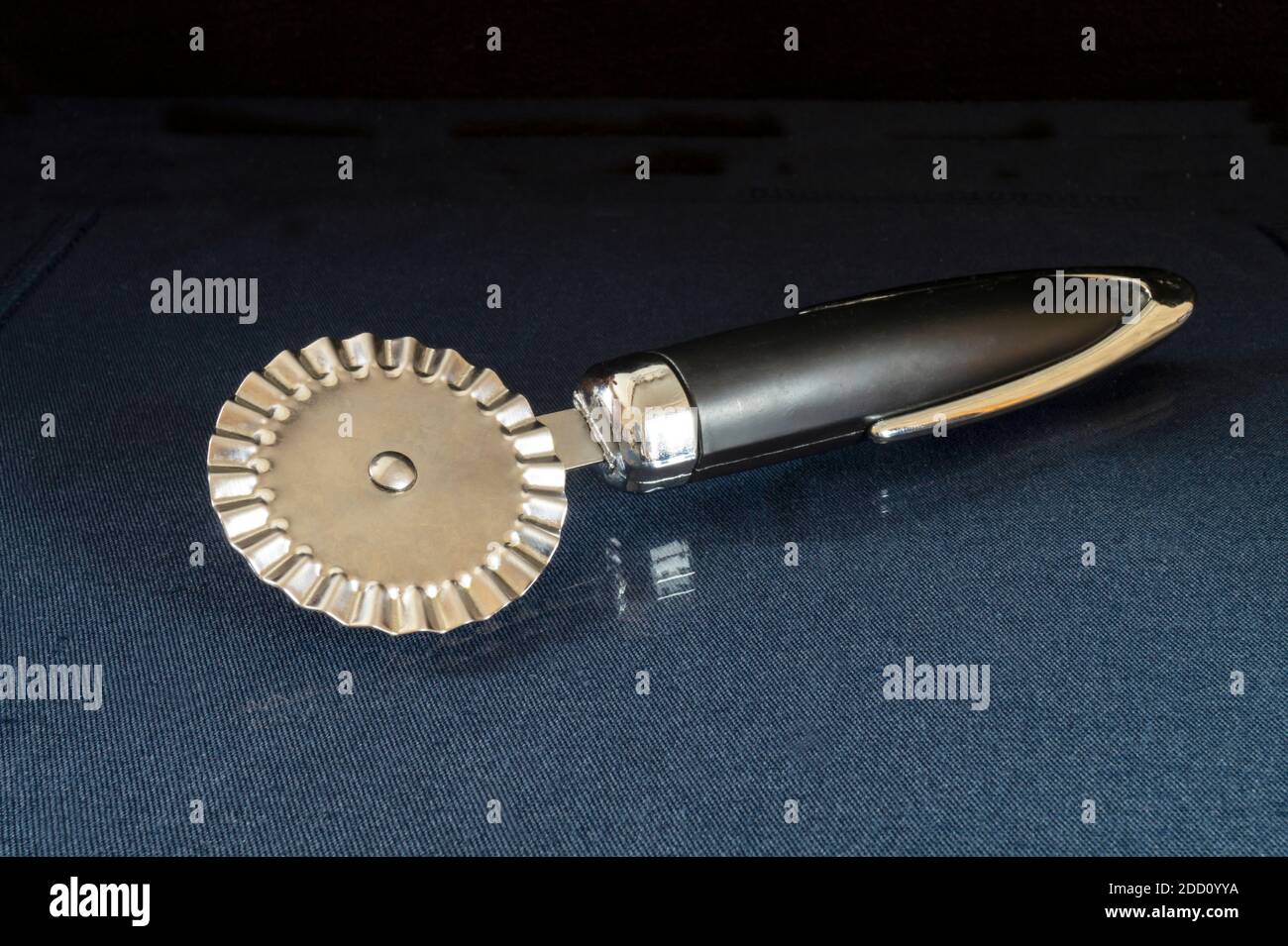 The Round knife for pizza rests upon table with reflection. Brilliant ...