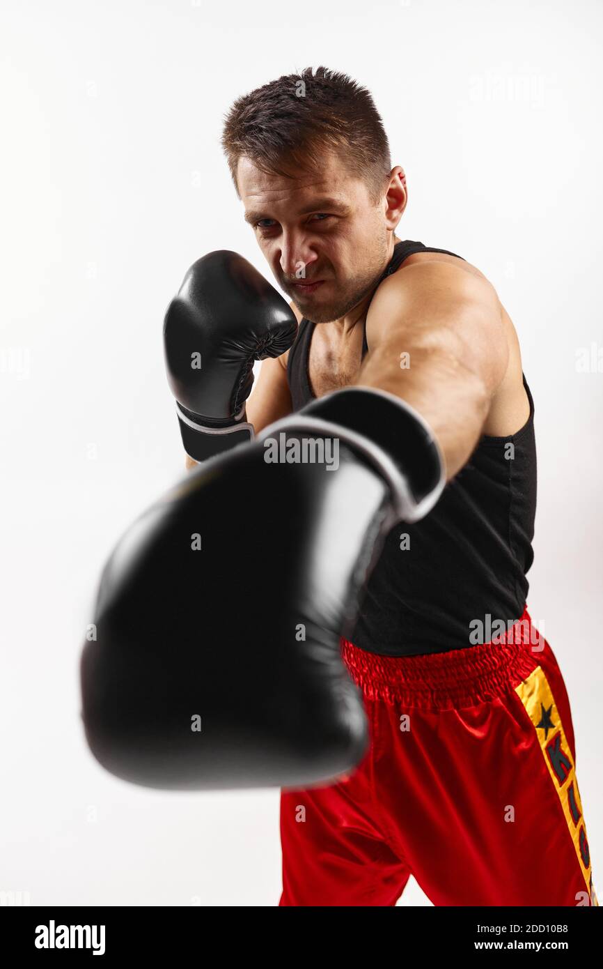 Aggressive boxer in black boxing gloves punching isolated on white ...