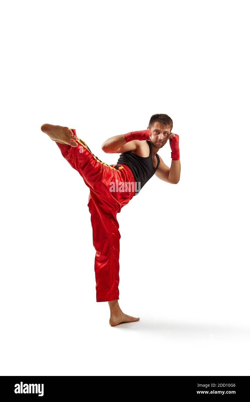 Athletic man in red sports bandages on his hands making kick during ...
