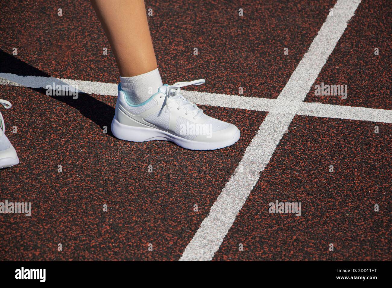 athlete's foot in sneakers starts from white stripe on asphalt pavement ...