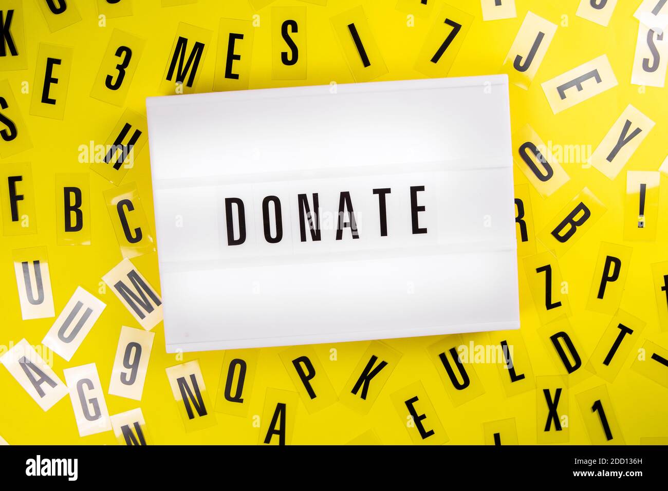 Donate word on lightbox on scattered letters background of plastic ...