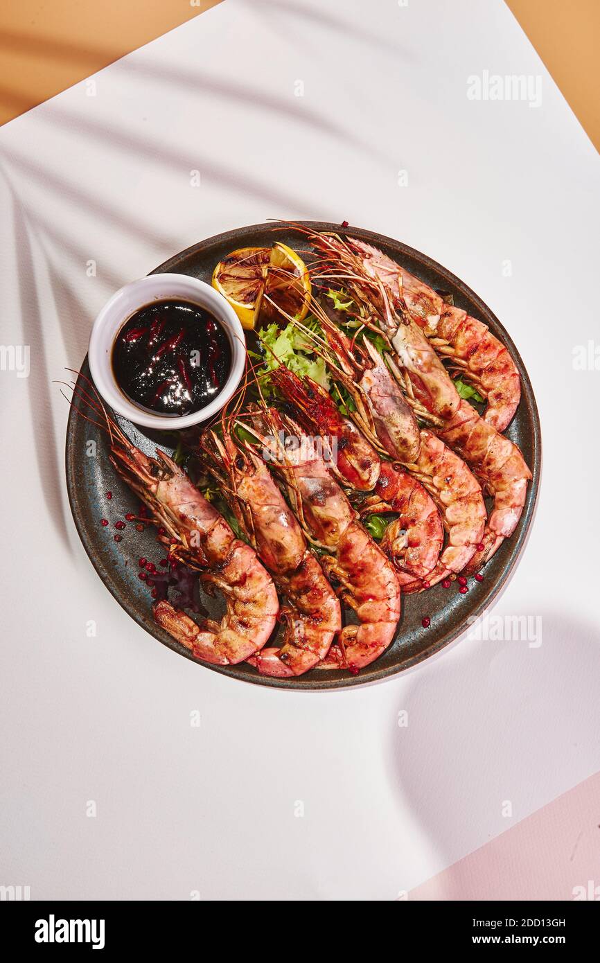 Grilled king prawns with sauce on a platter on modern colored ...