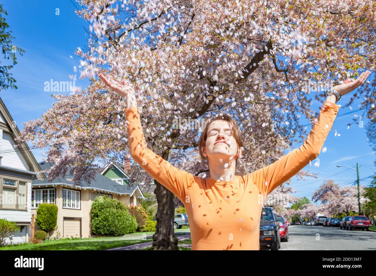 Happy woman throwing tree blossom petals in the air during Spring in ...