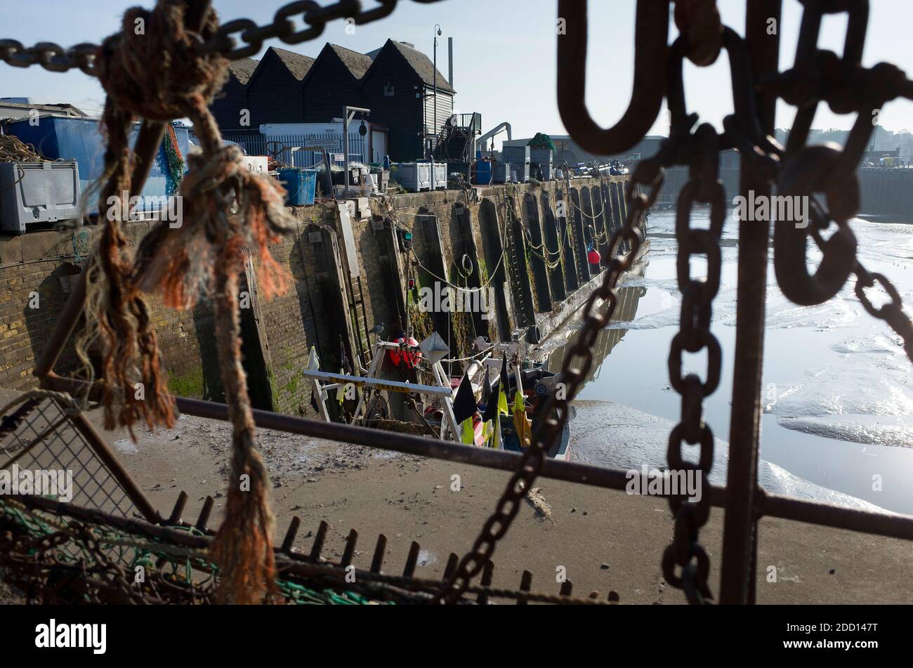 View through chains and railings of a British fishing boat stuck in dry ...
