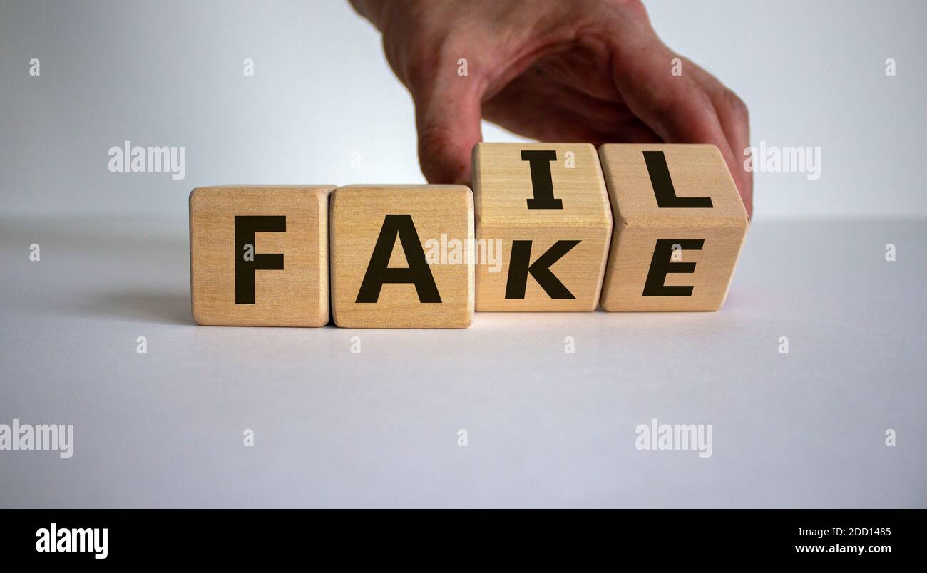 Fail fake. Male hand flips wooden cubes with words 'fail, fake' on ...
