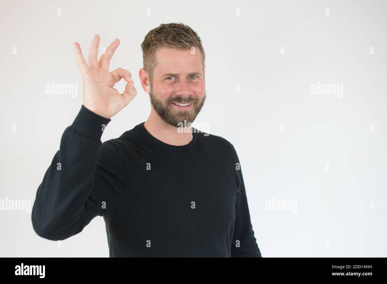 Portrait of a happy man showing okay gesture over white background ...