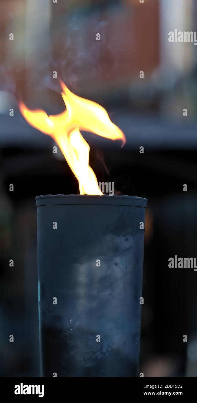 Black iron torch with yellow and orange live flame and blurred ...