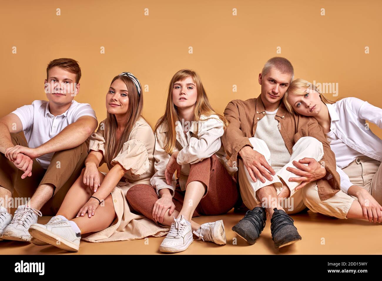 friendly group of students youth on the floor in studio on brown ...