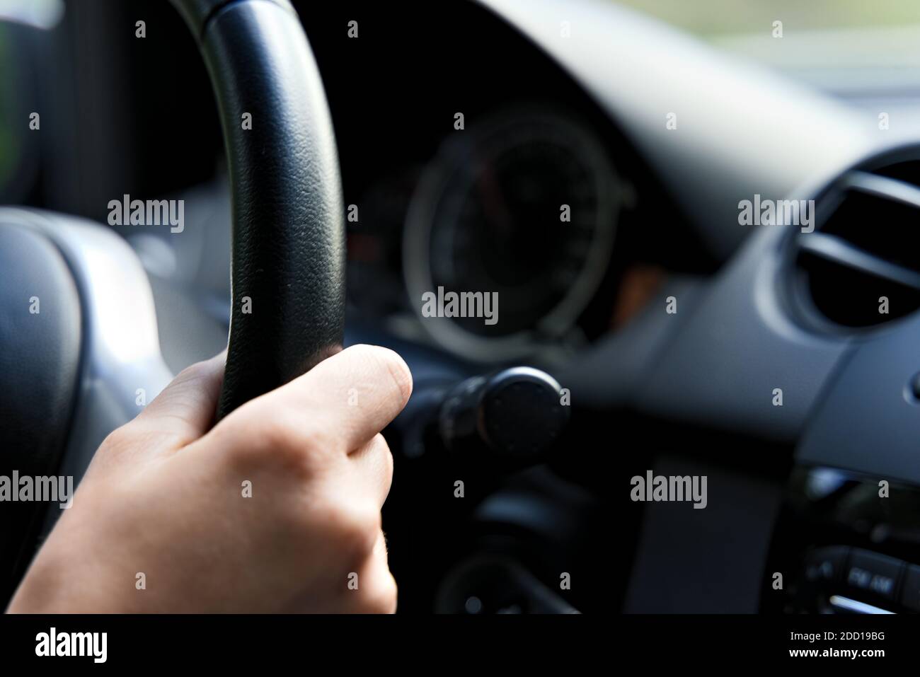 Female hand on steering wheel of a car while driving. Black interior ...