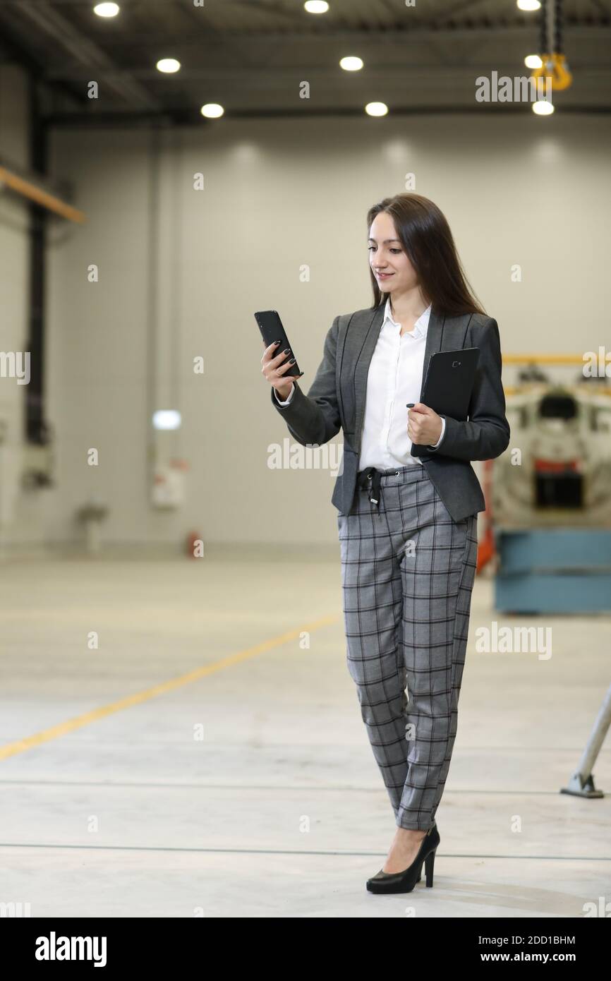 Portrait of a female factory manager in a white hard hat and business ...