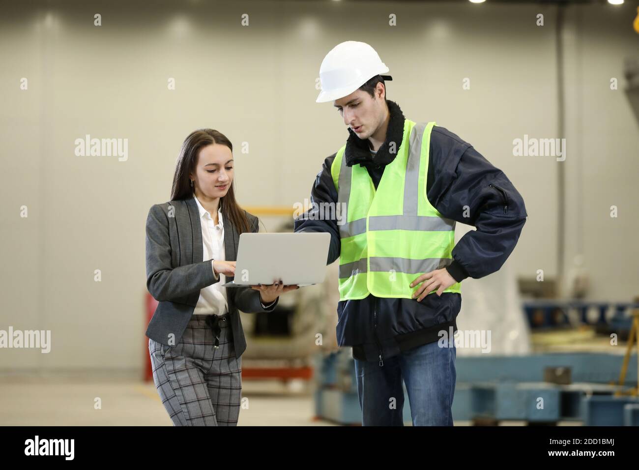 Portrait of a female factory manager in a white hard hat and business ...