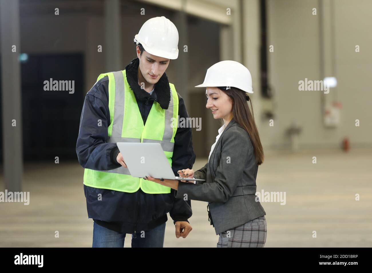Portrait of a female factory manager in a white hard hat and business ...