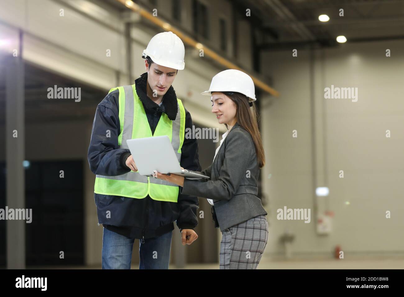 Portrait of a female factory manager in a white hard hat and business ...