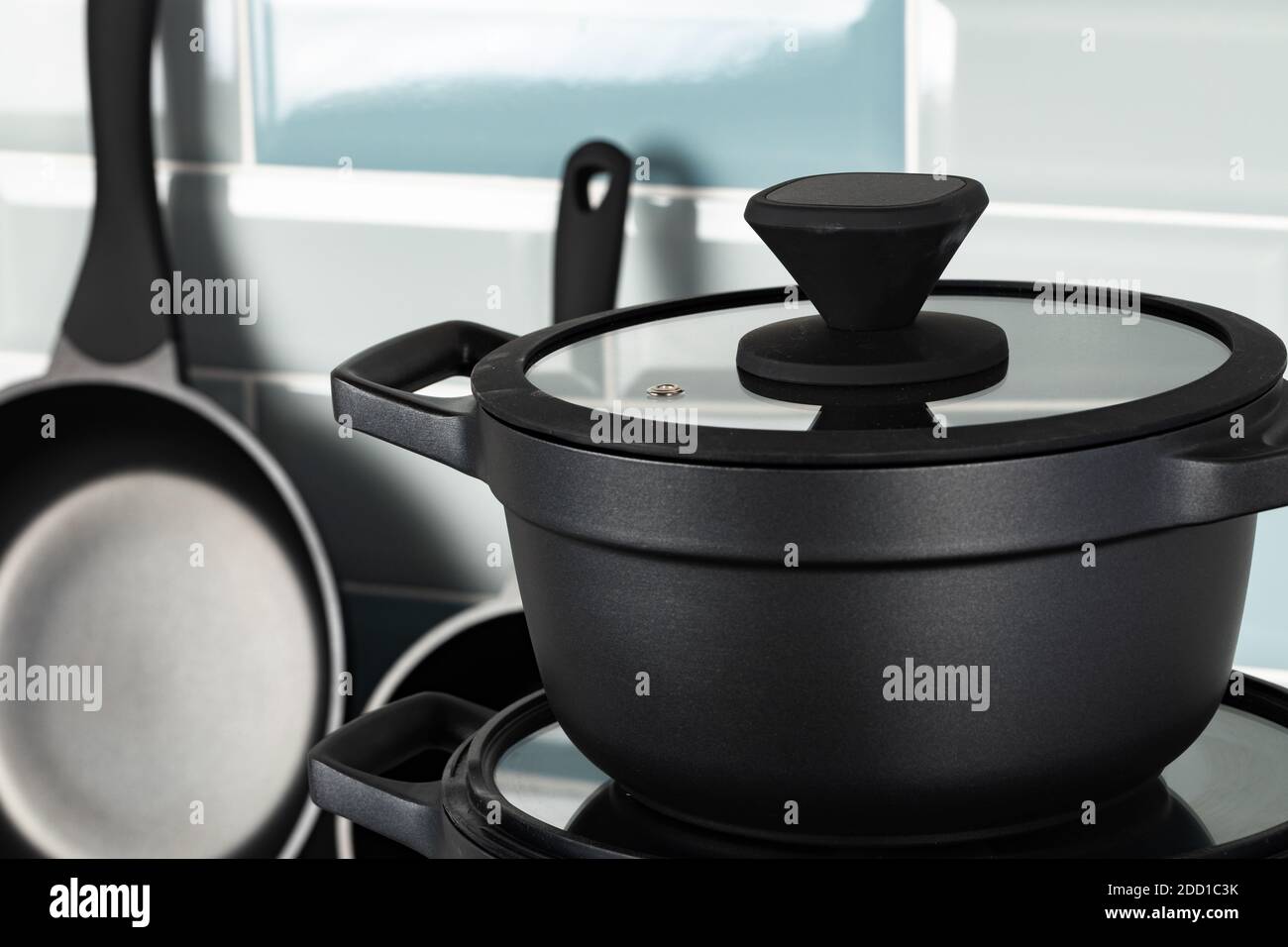 New black cookware against blue tile wall Stock Photo - Alamy