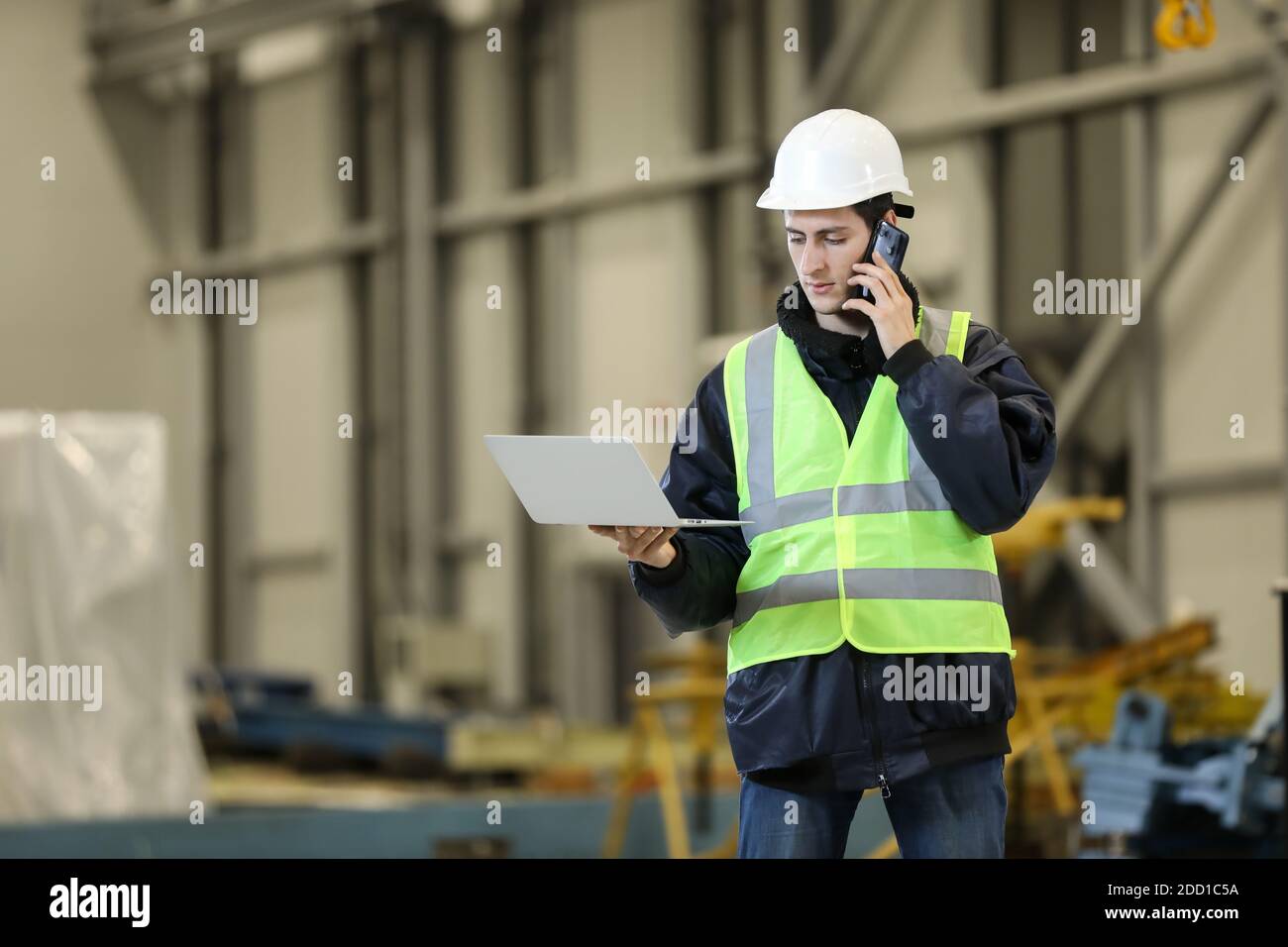 Portrait of a man , factory engineer in work clothes holding laptop and ...