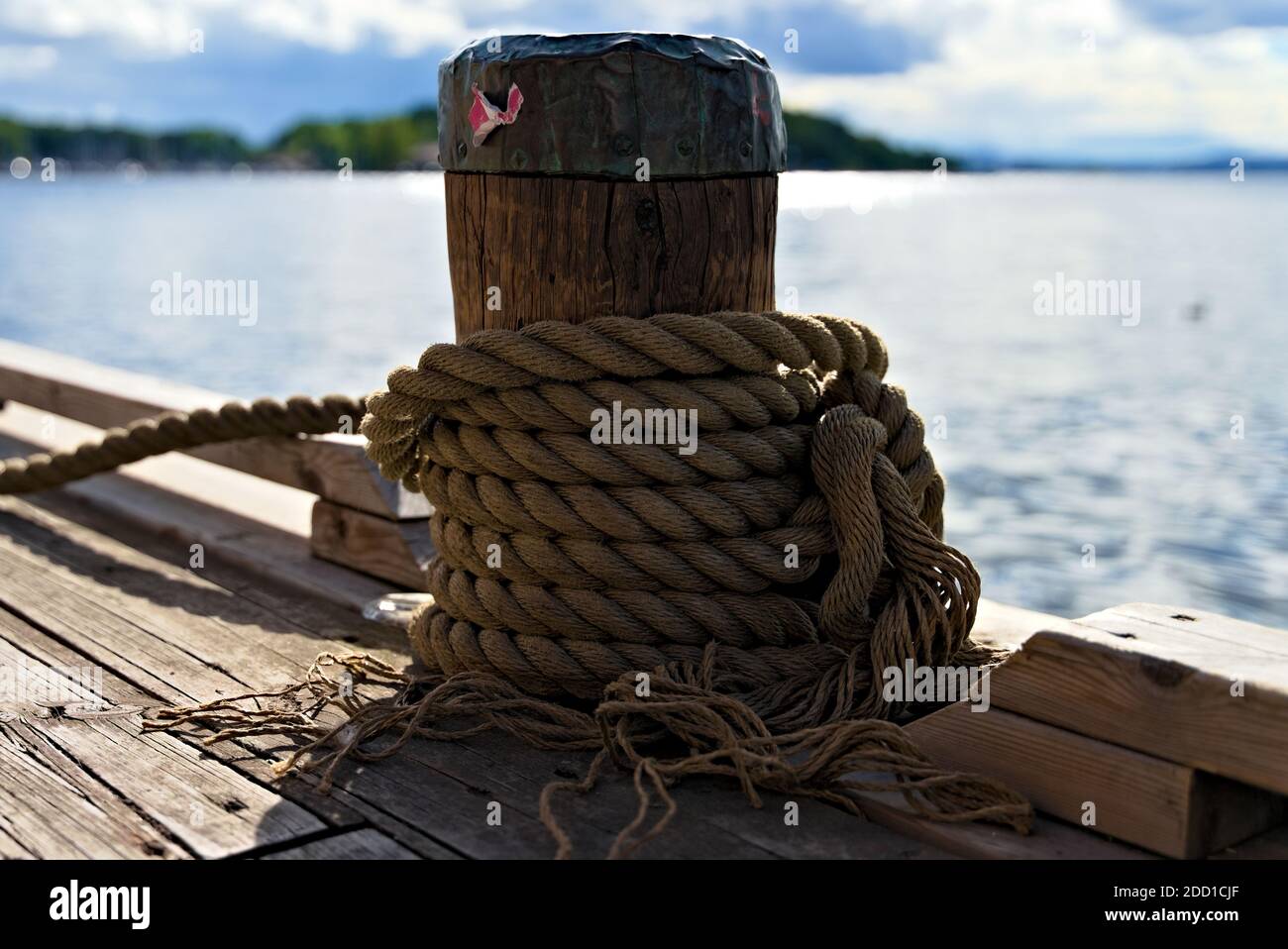 Maritime hemp rope moorings from a ship tied around an old wood bollard ...