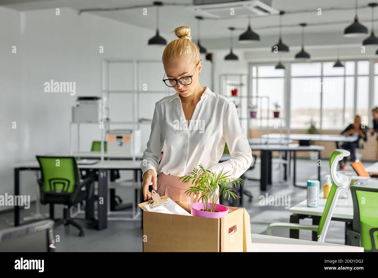 unhappy female employee packing things at work, she is fired from work ...