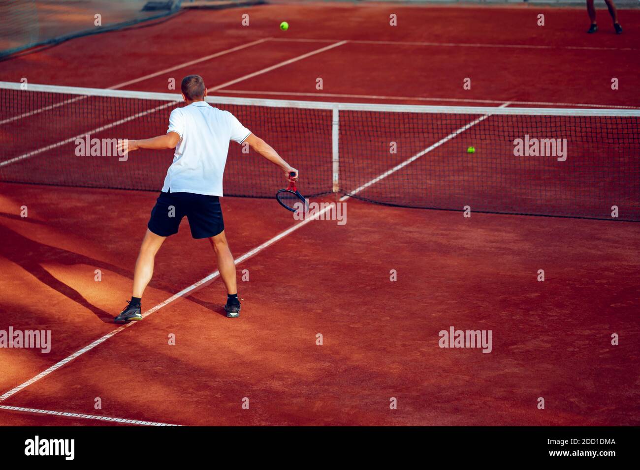 Back view of a man playing tennis on tennis court Stock Photo - Alamy
