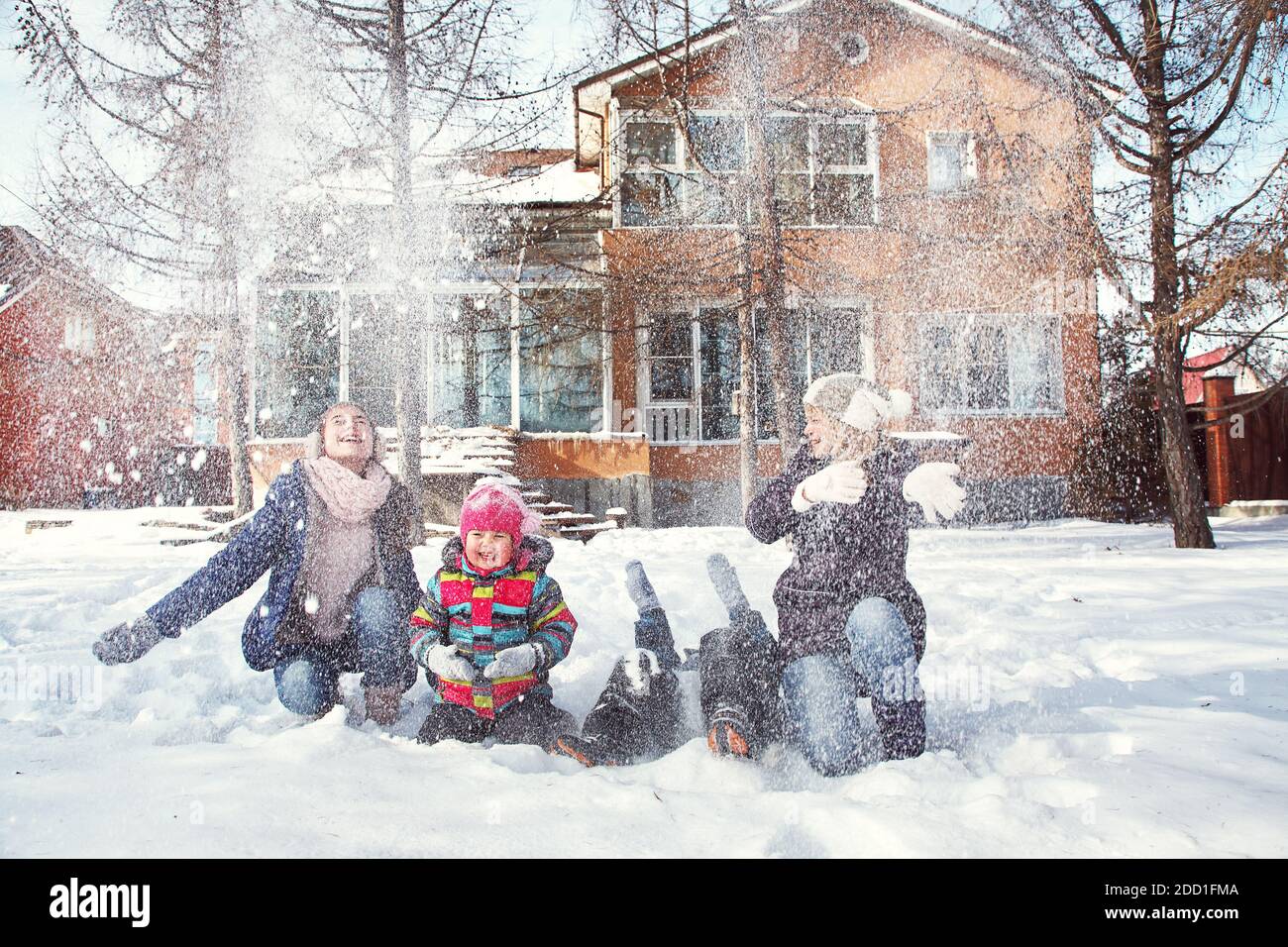 family playing with snow in the yard of his house in the winter ...