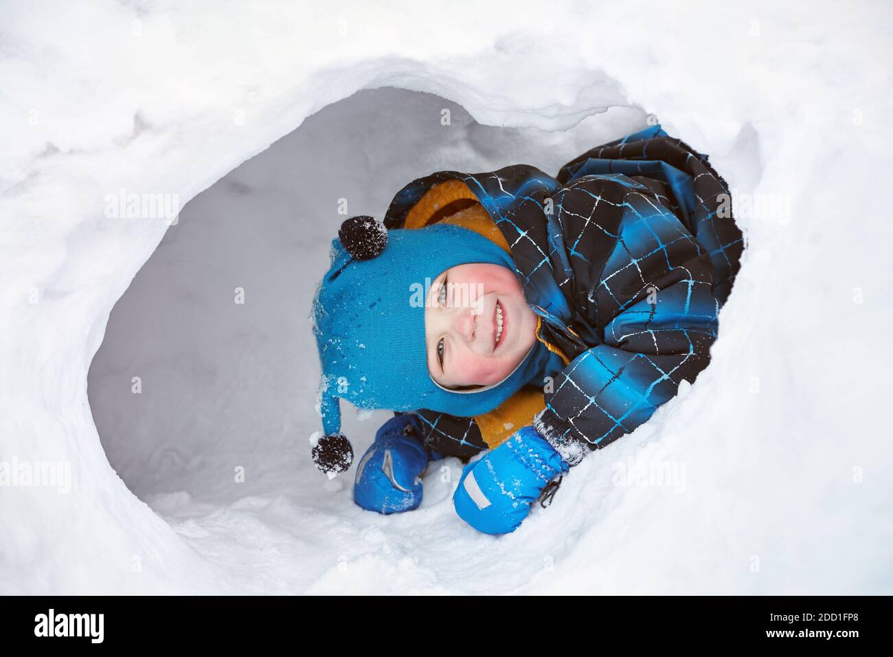 funny little boy playing with snow. child in snow house in the winter ...