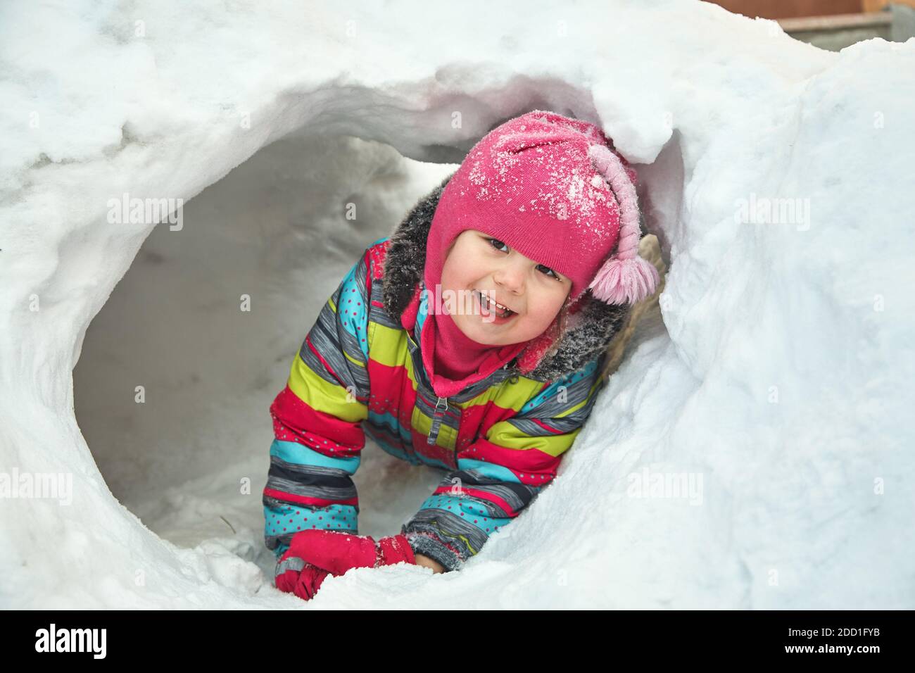 funny little girl playing with snow. child in snow house in the winter ...