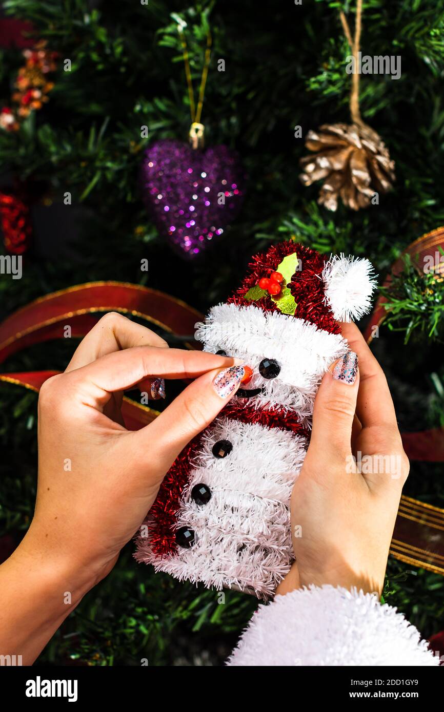 Hands holding Christmas snowman figurine in front of the Christmas tree ...