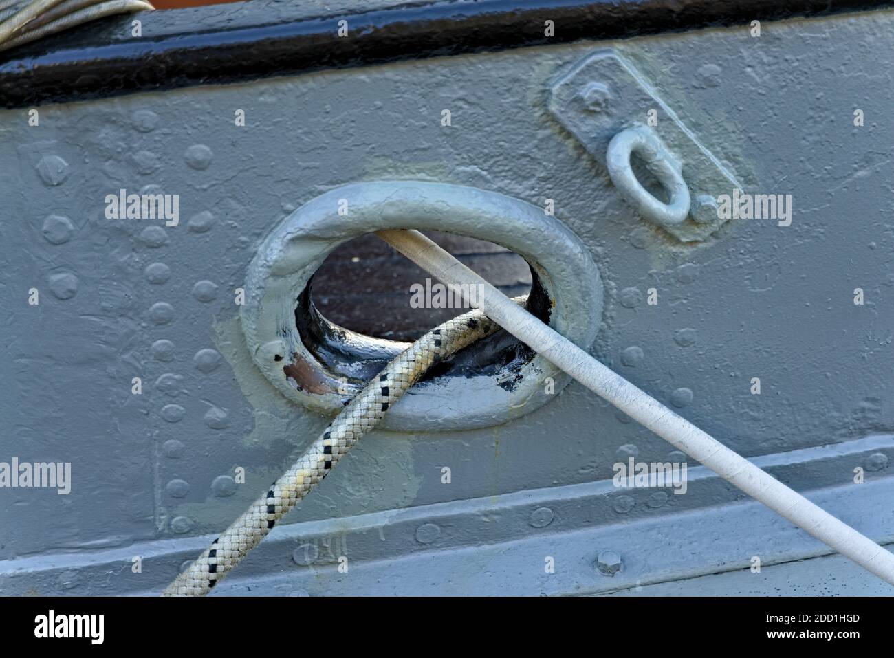 Mooring lines going from a cleat hole on a white steel ship at port ...