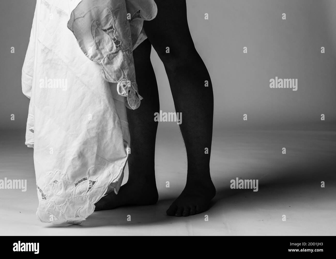 A grayscale shot of the feet of a person wearing a white dress in a ...